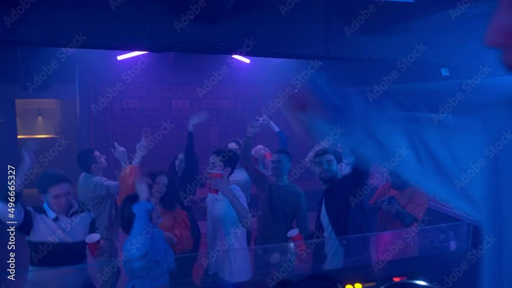 A crowd of people dancing on the dance floor of a nightclub under the ...