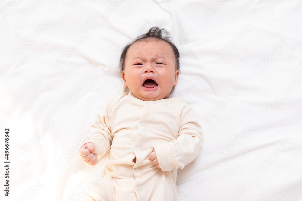 Crying and angry Newborn baby boy lying on white bed at home.Infant ...