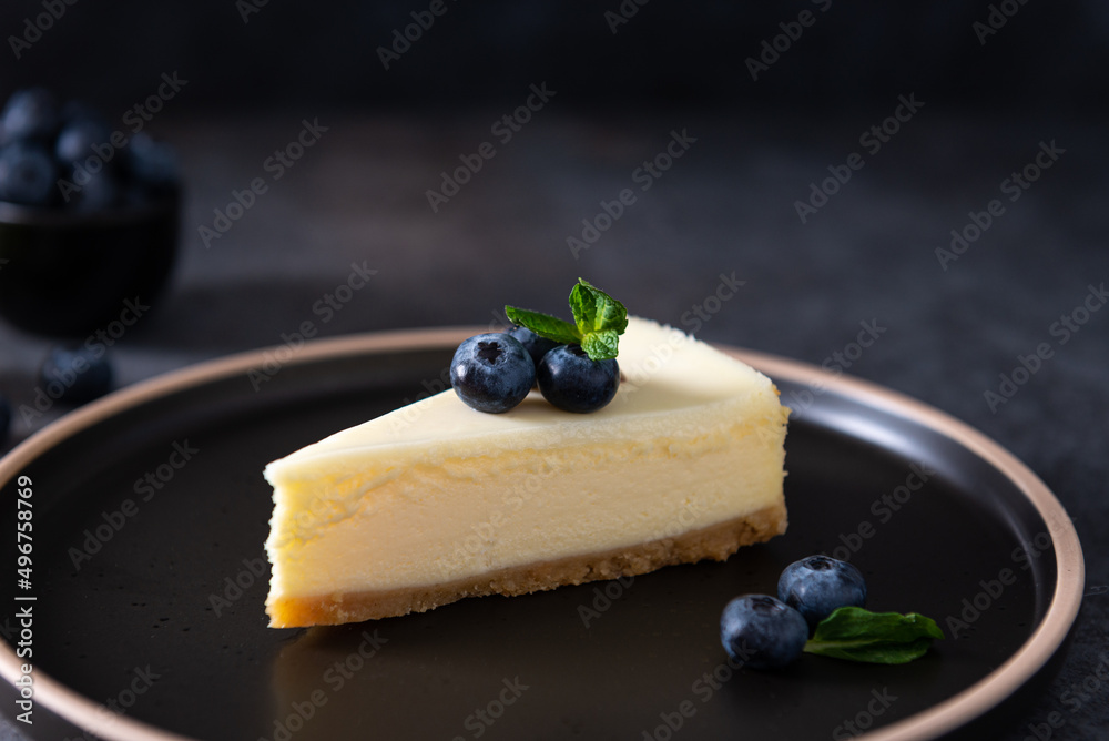 Classic New York cheesecake with fresh blueberries and mint on dark ...