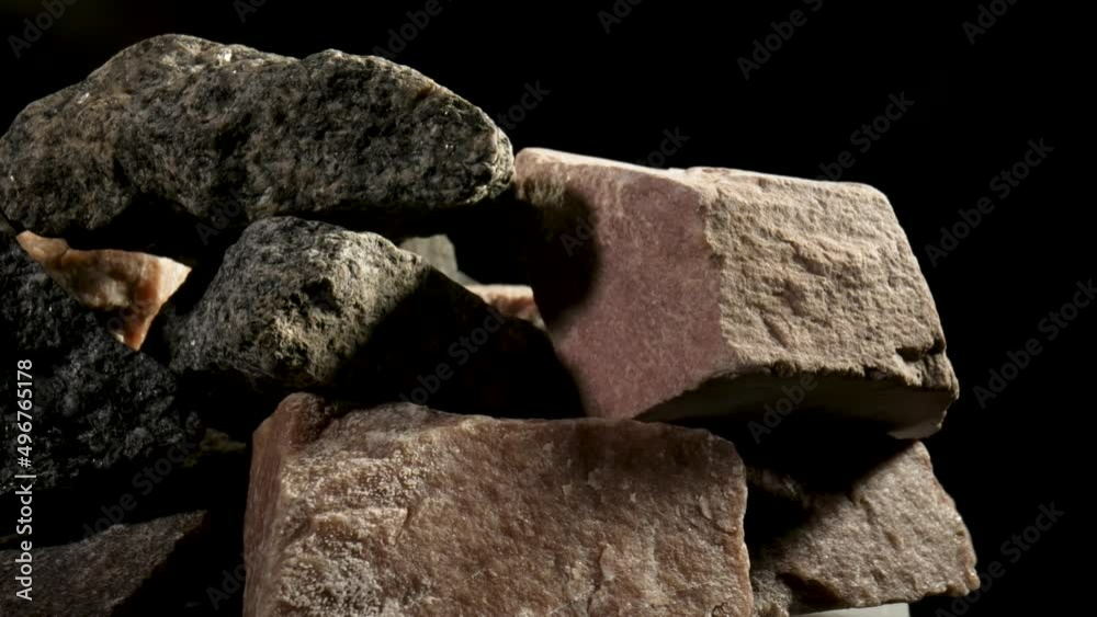 Pieces of solid rough granite stone rotating against a black studio ...