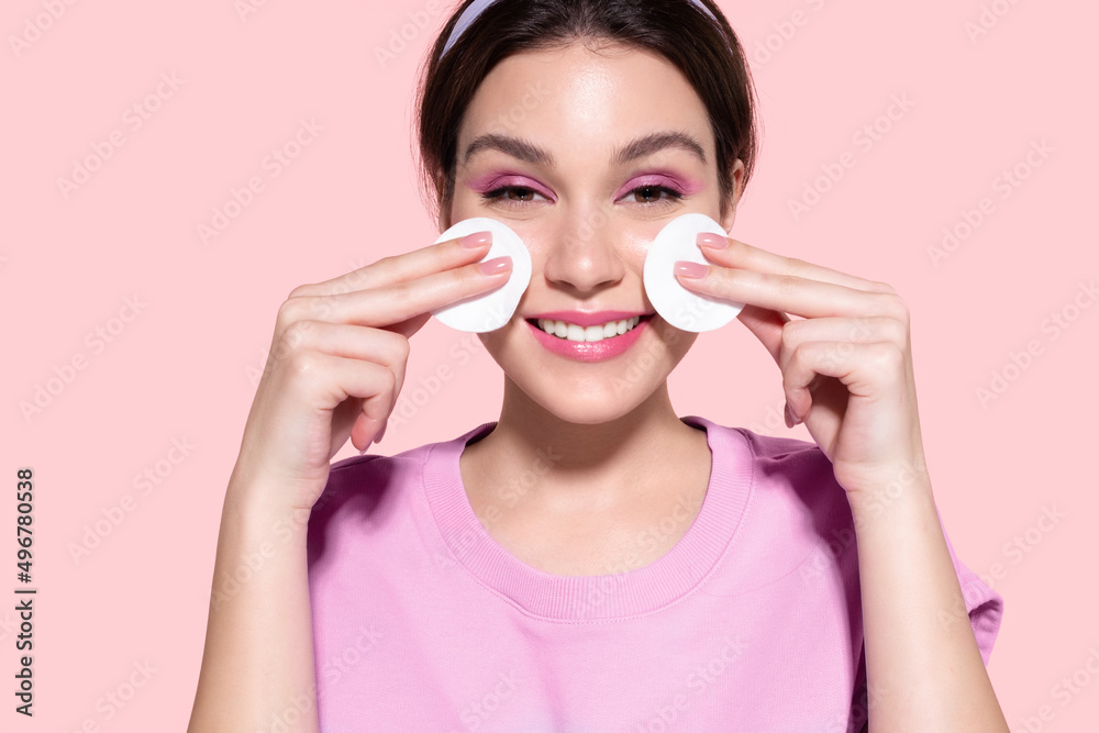 Smiling modern girl cleaning face skin, removing makeup, using cotton ...