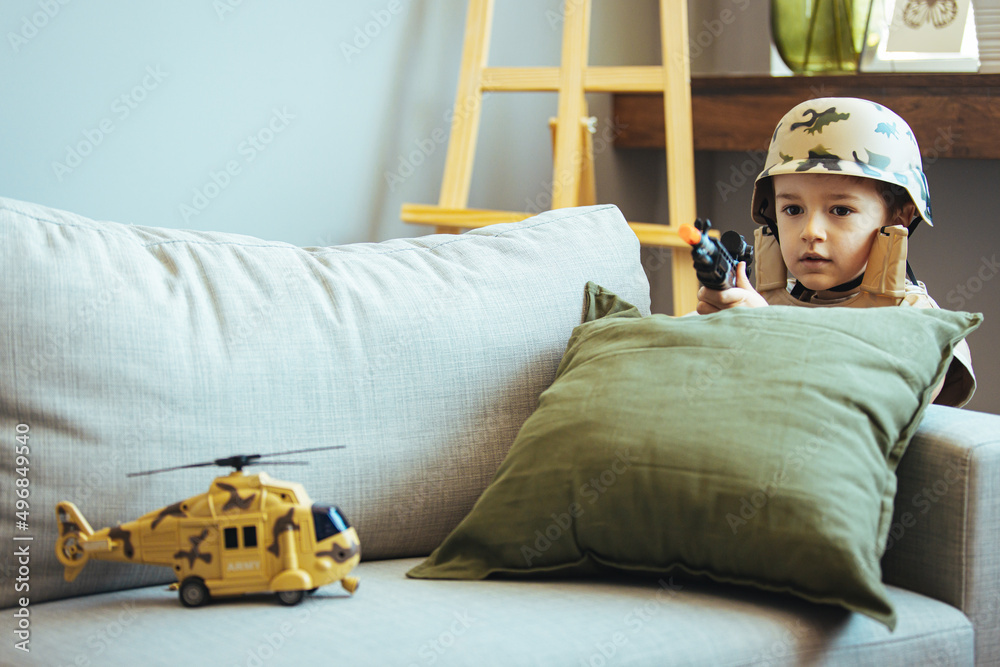 Little boy playing soldiers in living room. In his imagination the boy ...
