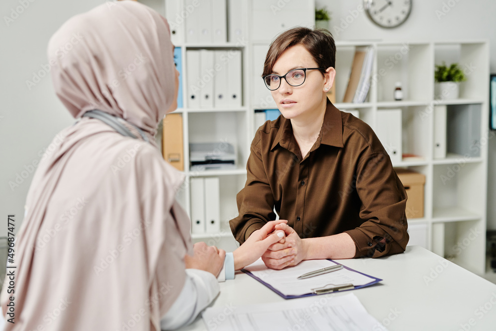 Foto de Young sick female patient looking at Muslim doctor in hijab ...
