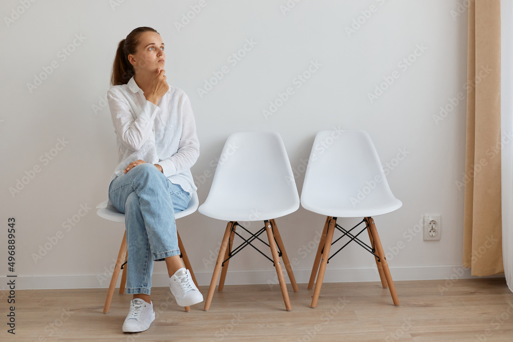Full length portrait of thoughtful confused woman wearing white shirt ...