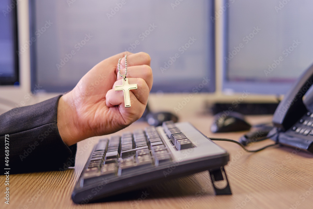 A businessman man with a religious Catholic cross in his hands is ...