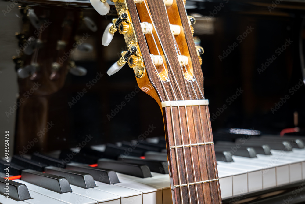 classical guitar against grand piano keys - musical instruments closeup ...