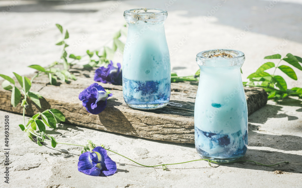 Butterfly pea blue tea latte, Served in a jar. Topping with white milk ...
