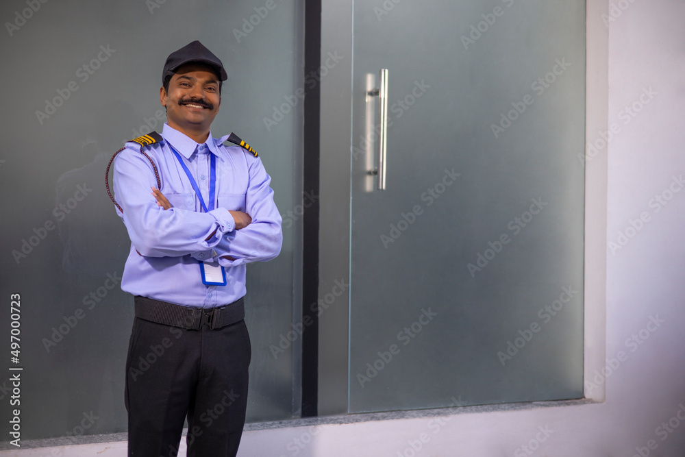 Portrait of security guard with arms folded while working at gate Stock ...