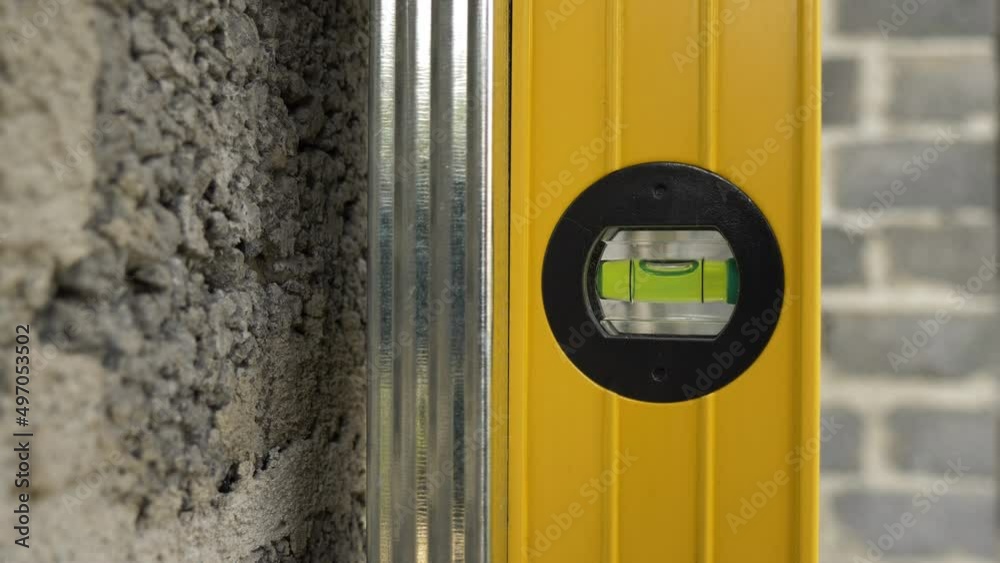 Liquid balance ruler. Installing metal profile frame on the brick wall ...