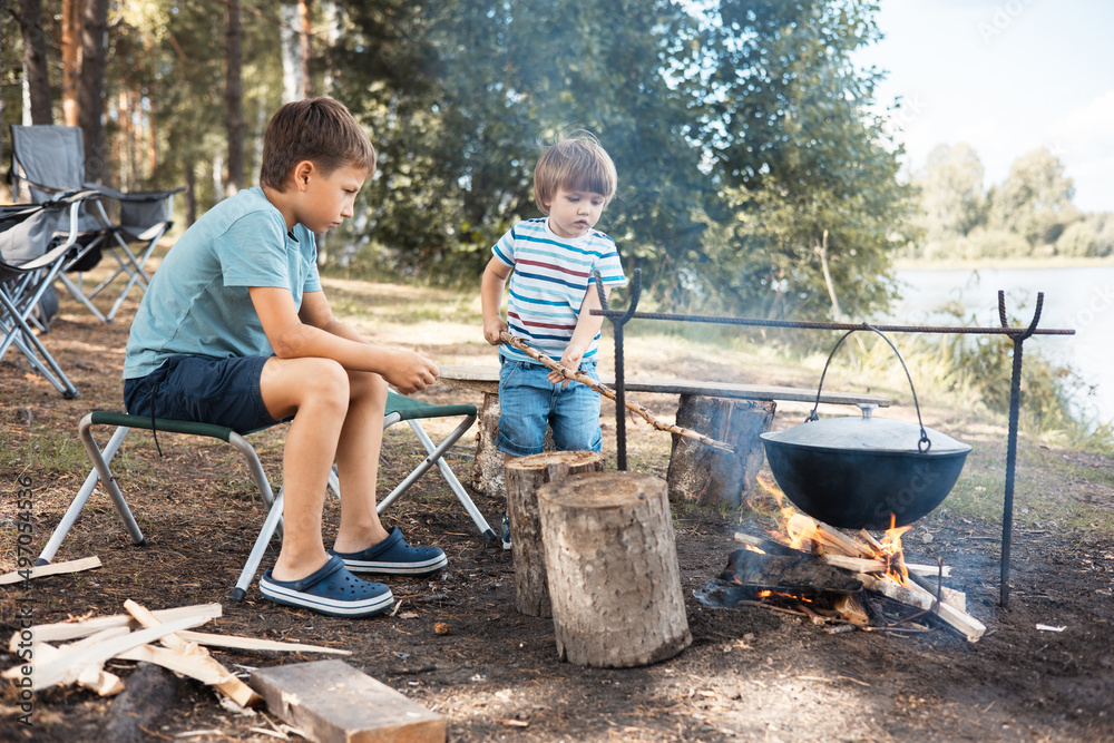 Children sitting around a campfire in forest in summer. Family picnic ...