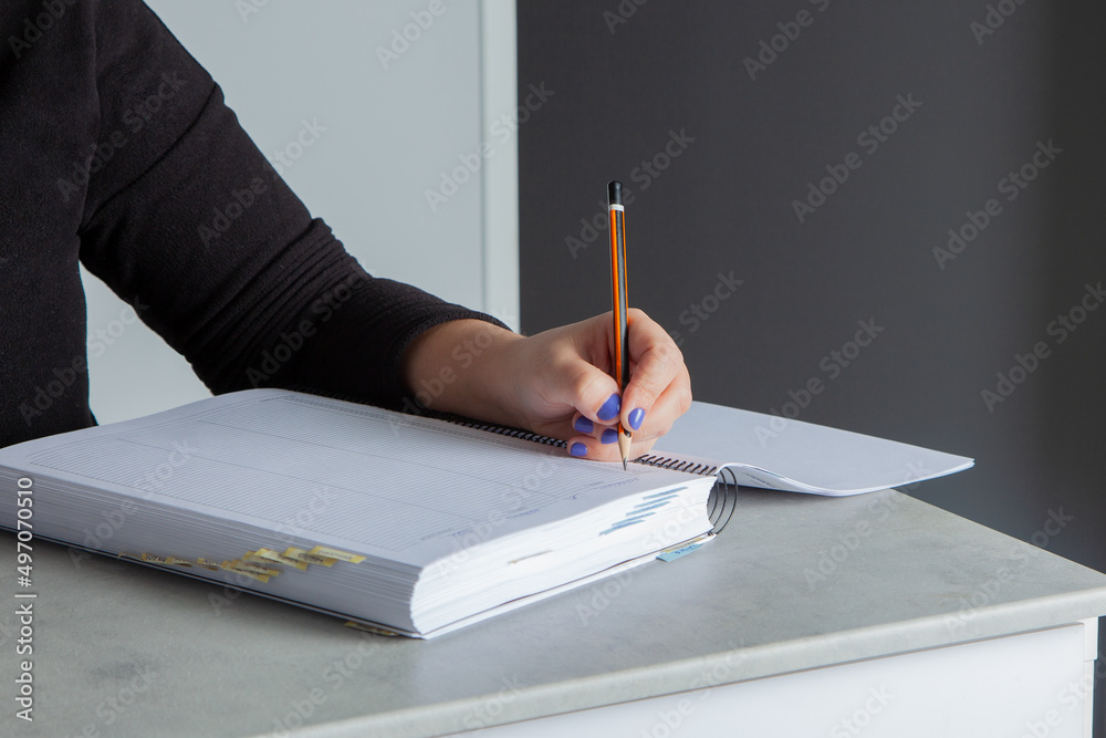 Mujer escribiendo en un cuaderno con un lapicero Stock Photo | Adobe Stock