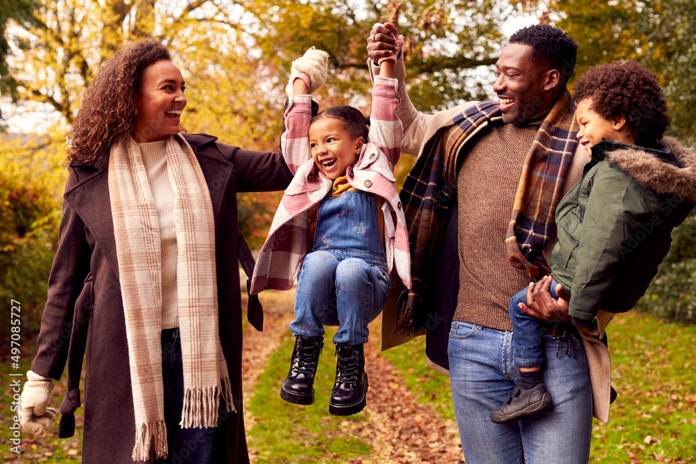 Smiling Family Having Fun Swinging Daughter On Walk Through Countryside ...