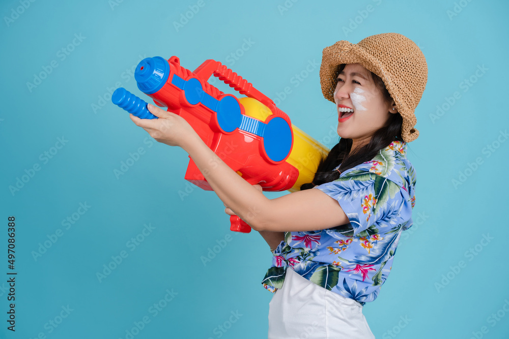 Beautiful Asian girl playing with water guns isolated on studio blue ...