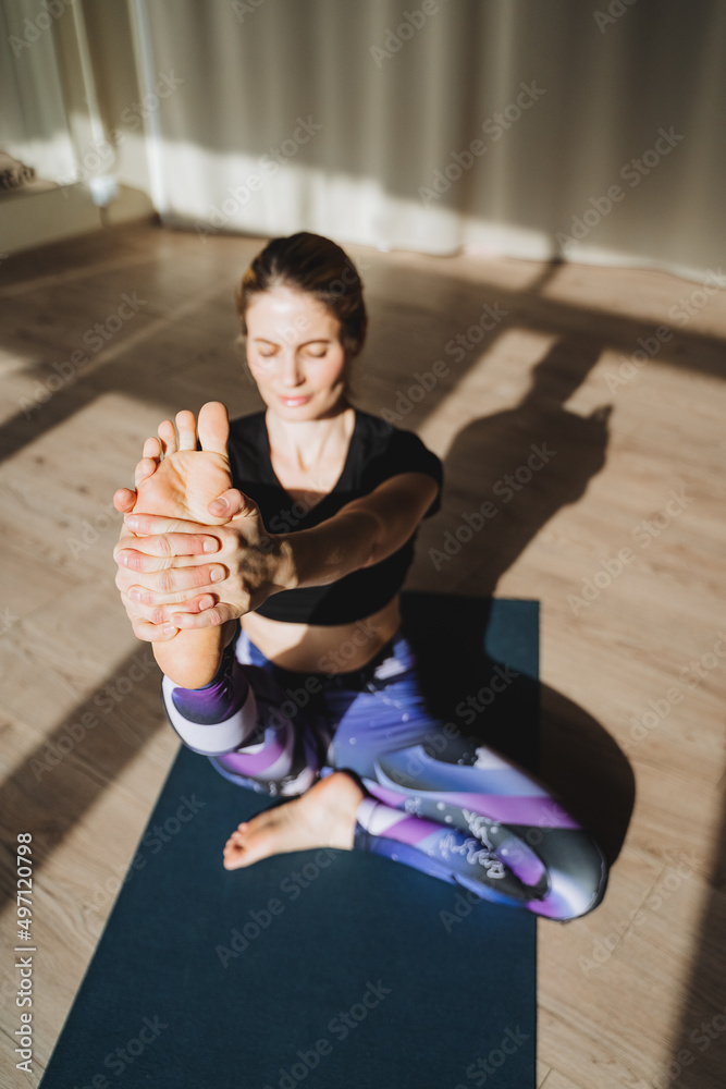 Janushirasana sitting on the floor, the girl stretches her leg grip ...