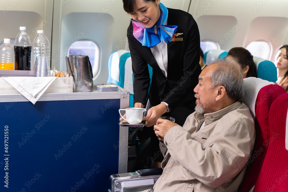 Young beautiful Asian flight attendant serving food and drink to ...