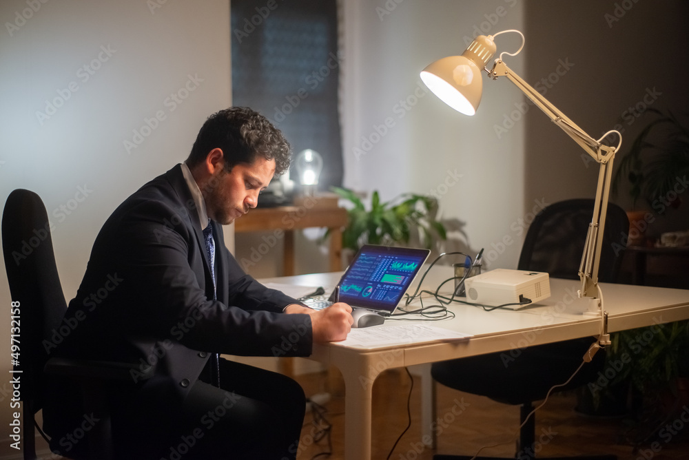 Side view of serious young man working. Man in suit sitting at laptop ...