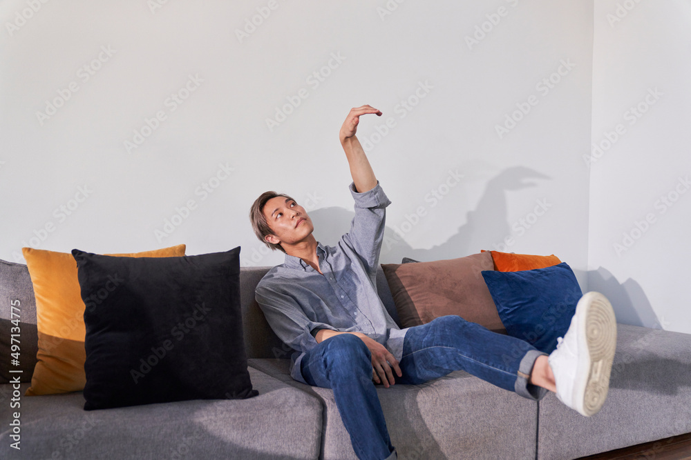 Man dancing while sitting on sofa with arm raised and leg extended ...