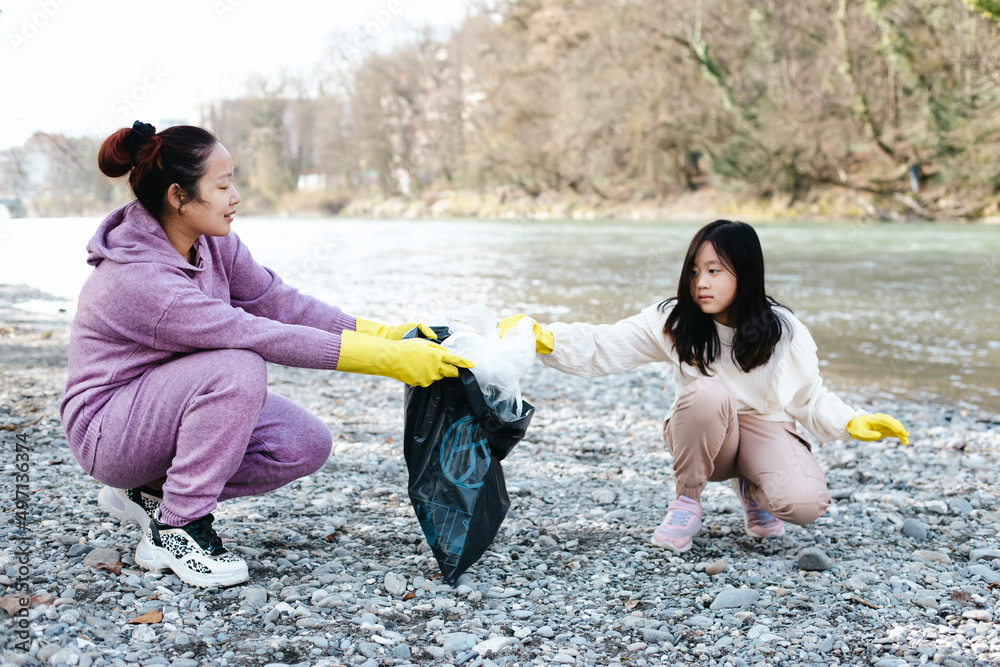 Earth Day concept, Woman and daughter pick up garbage in litter bags ...