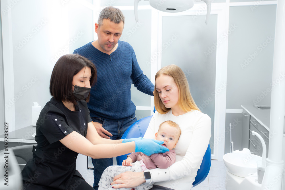Young parents and their daughter visit a dentist to examine milk teeth ...