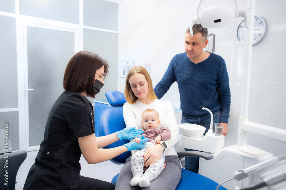 Young Parents And Their Daughter Visit A Dentist To Examine Milk Teeth