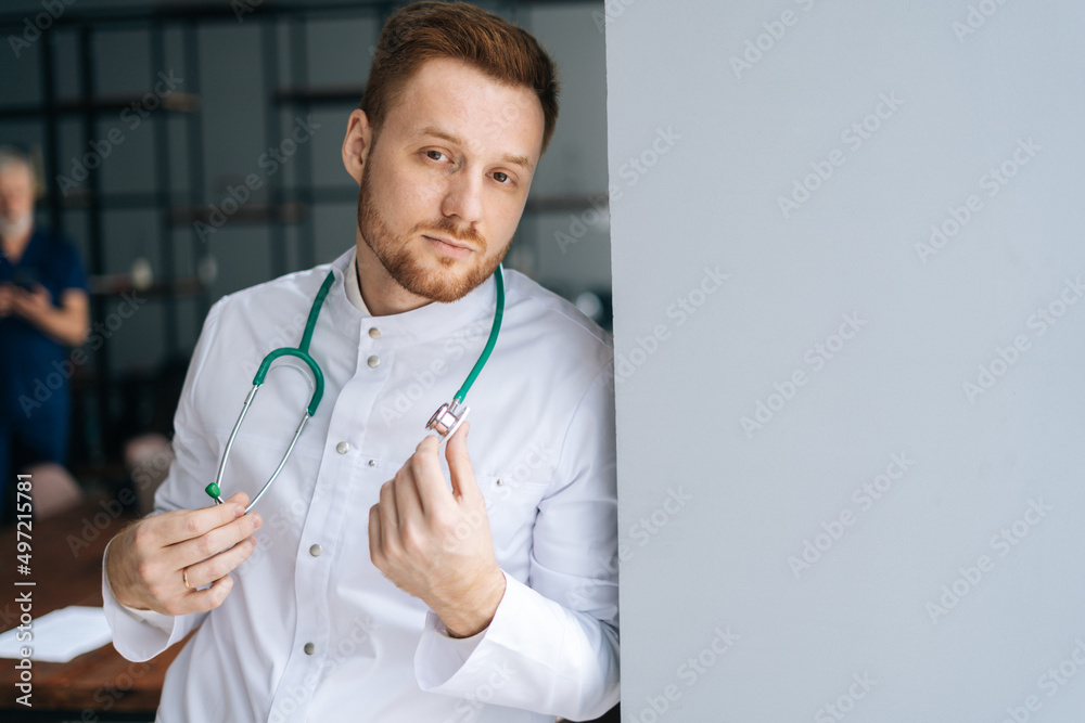 Portrait of handsome male doctor wearing white medical uniform standing ...