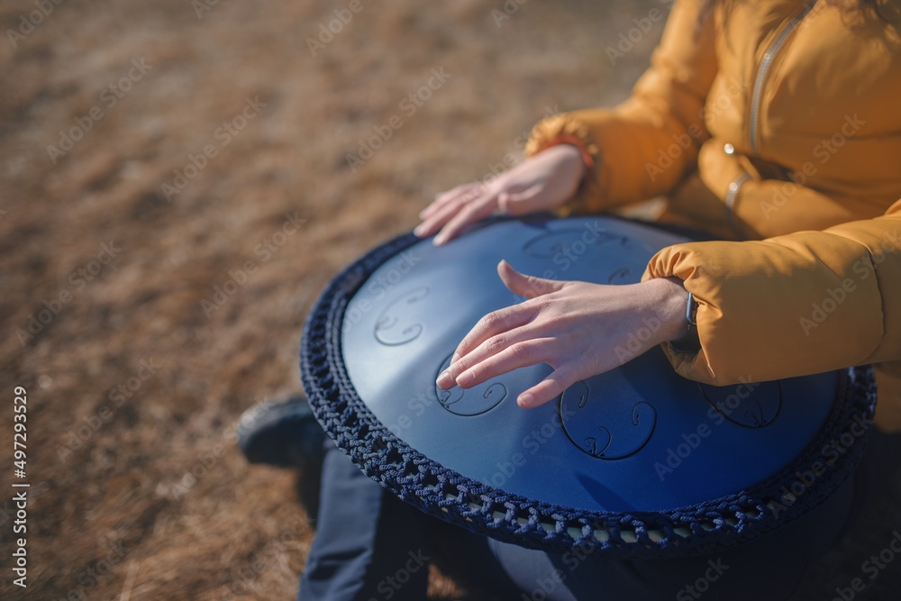 Female hands playing a tongue drum musical instrument (metal drum with ...