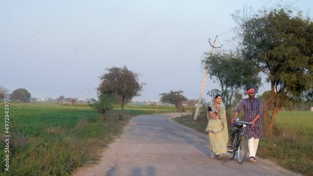 An Indian village couple going for a walk on a village road with a ...