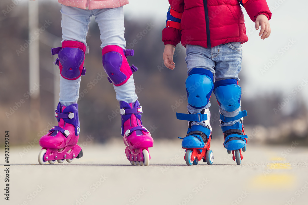 Kids boy and girl having fun outdoor while riding roller skates ...