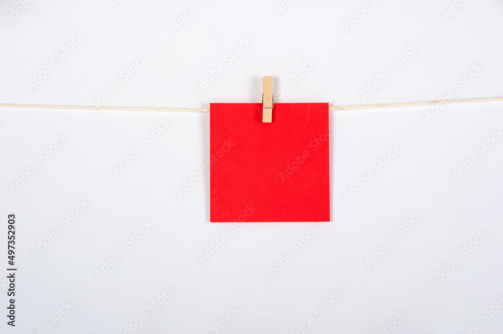 Post it rojo colgado con pinza sobre fondo blanco para concepto ...