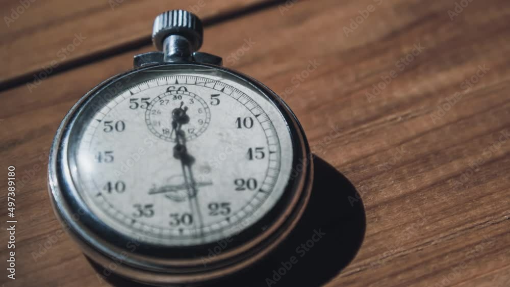 Antique stopwatch lies on wooden table and counts the seconds ...