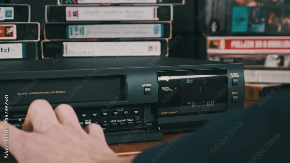 Insert VHS cassette into VCR and push play button. Black vintage ...