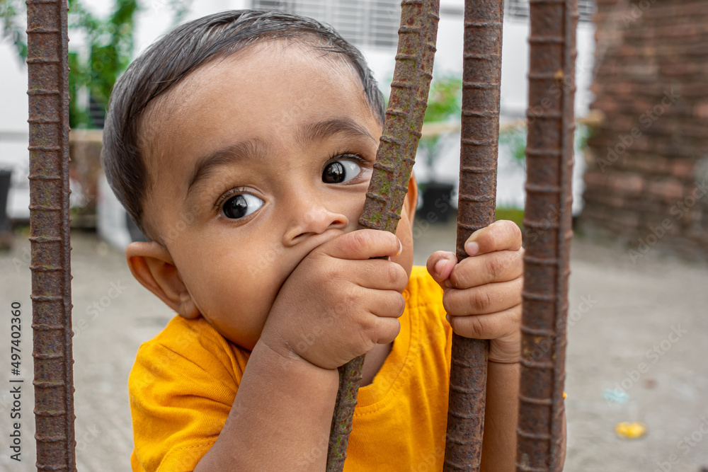 A infant child is trying to stand up holding a rusty iron rod in his ...