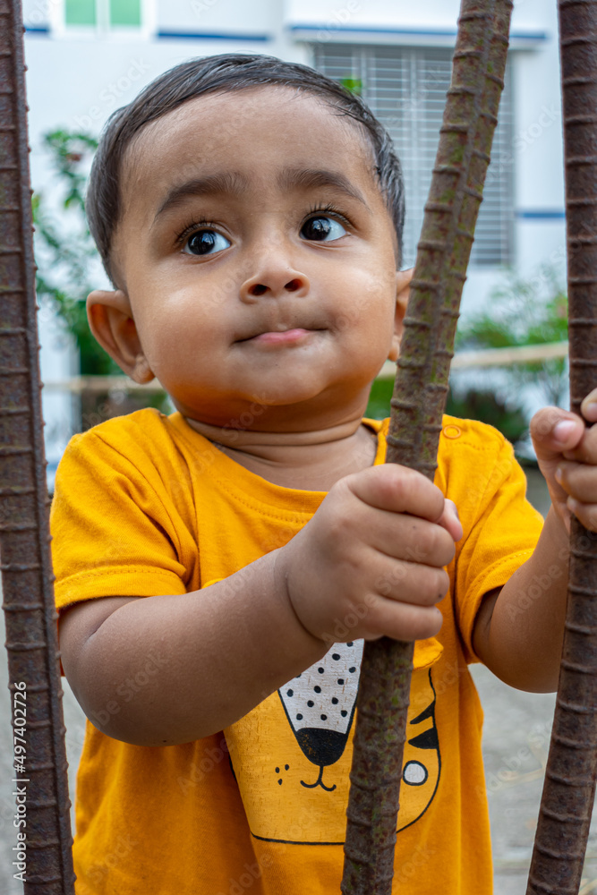 A infant child is trying to stand up holding a rusty iron rod in his ...