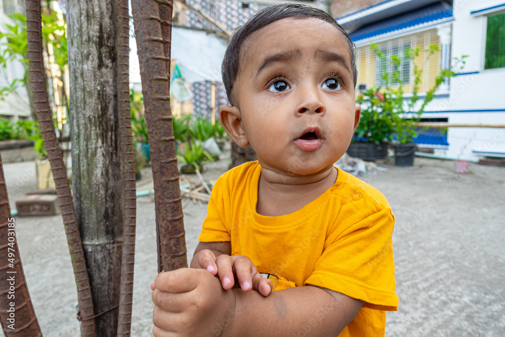A infant child is trying to stand up holding a rusty iron rod in his ...