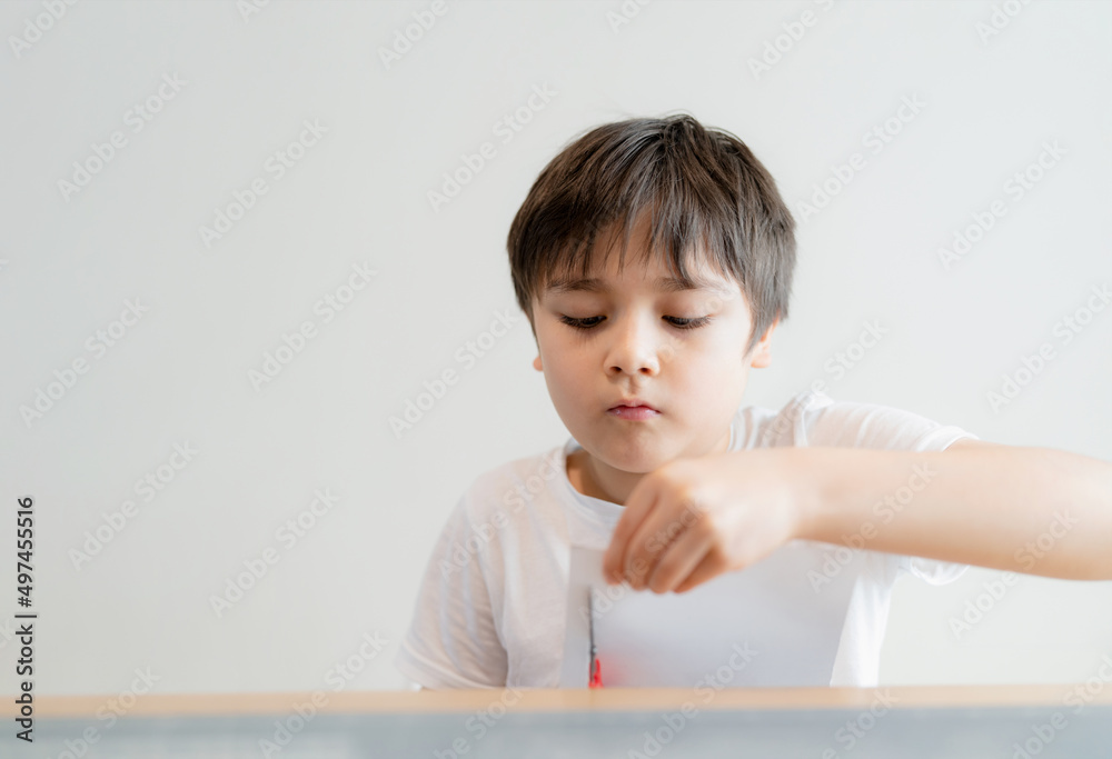 Kid using scissors cutting white paper , schoolboy making art and craft ...