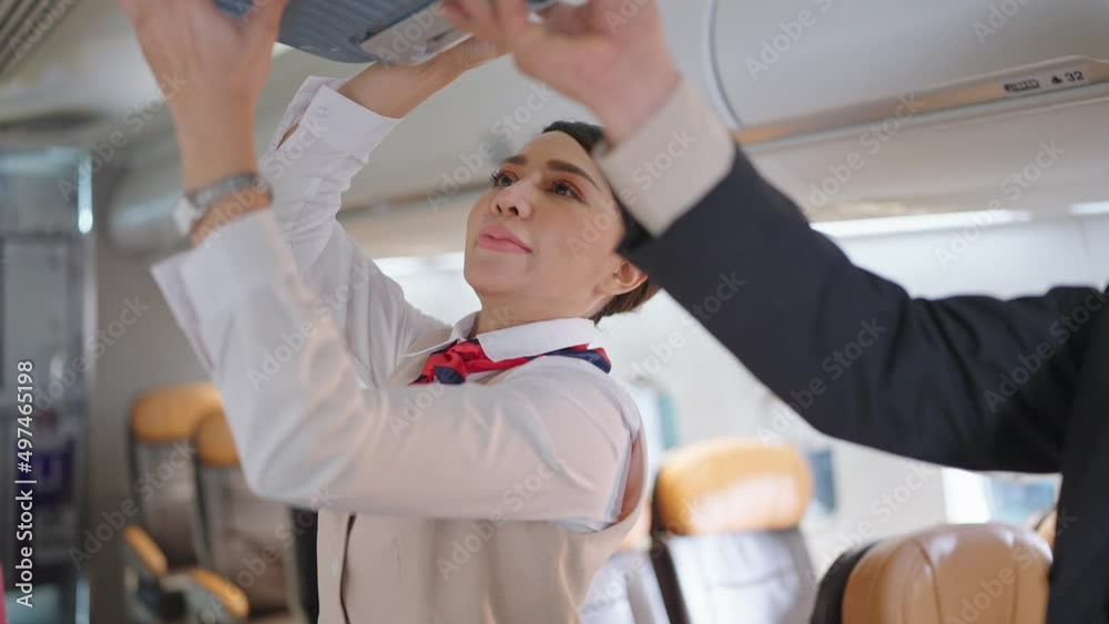 Cabin crew or air hostess helping passenger businessman put luggage on ...