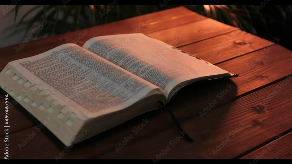 Open Bible on the table with pages flipped by the fan airflow vídeo do ...