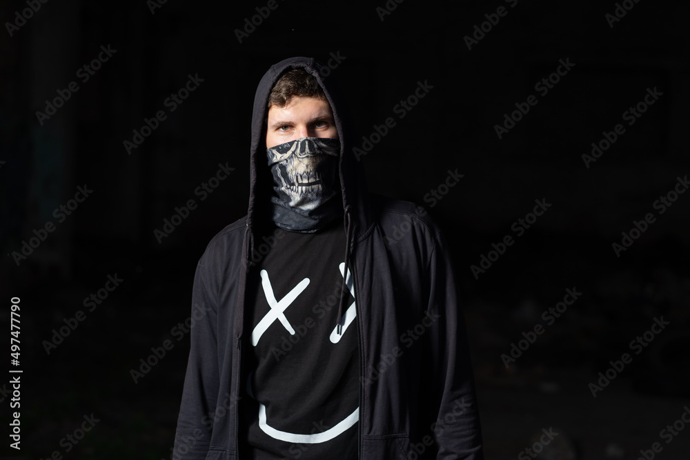 Foto de A young tough guy in a buff mask and hood . Hooligan, robber ...
