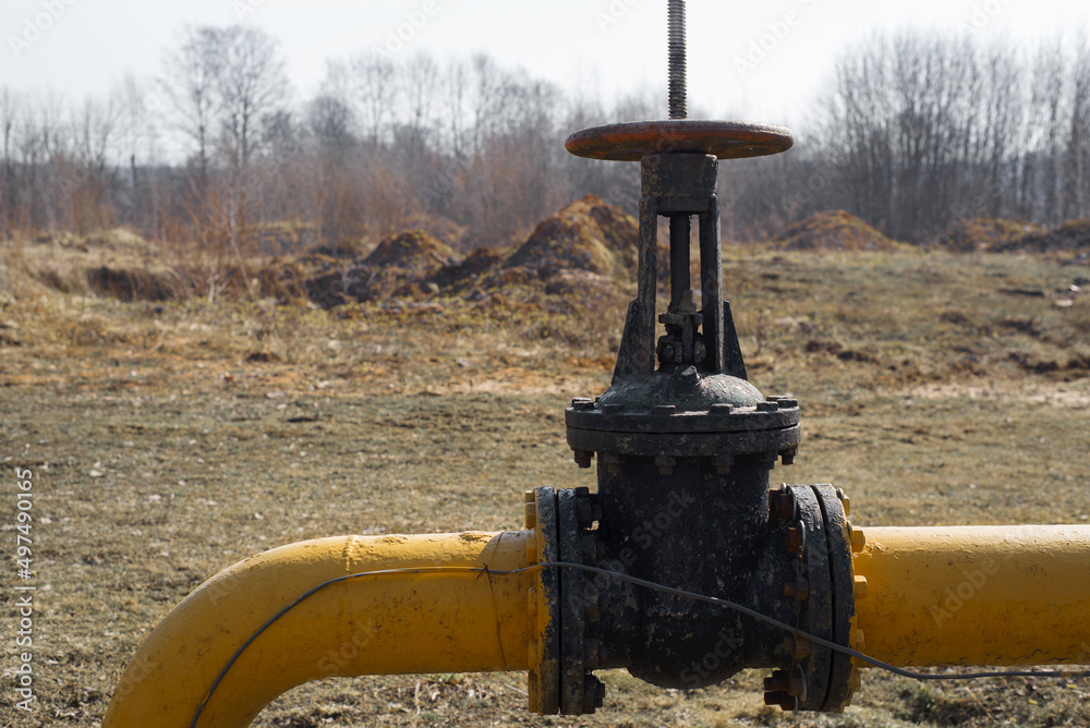 Side view of yellow gas pipe with gate valve to adjust supply, outdoors ...