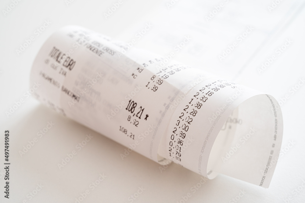 Rolled up shopping receipt, with some amounts visible, on a white ...