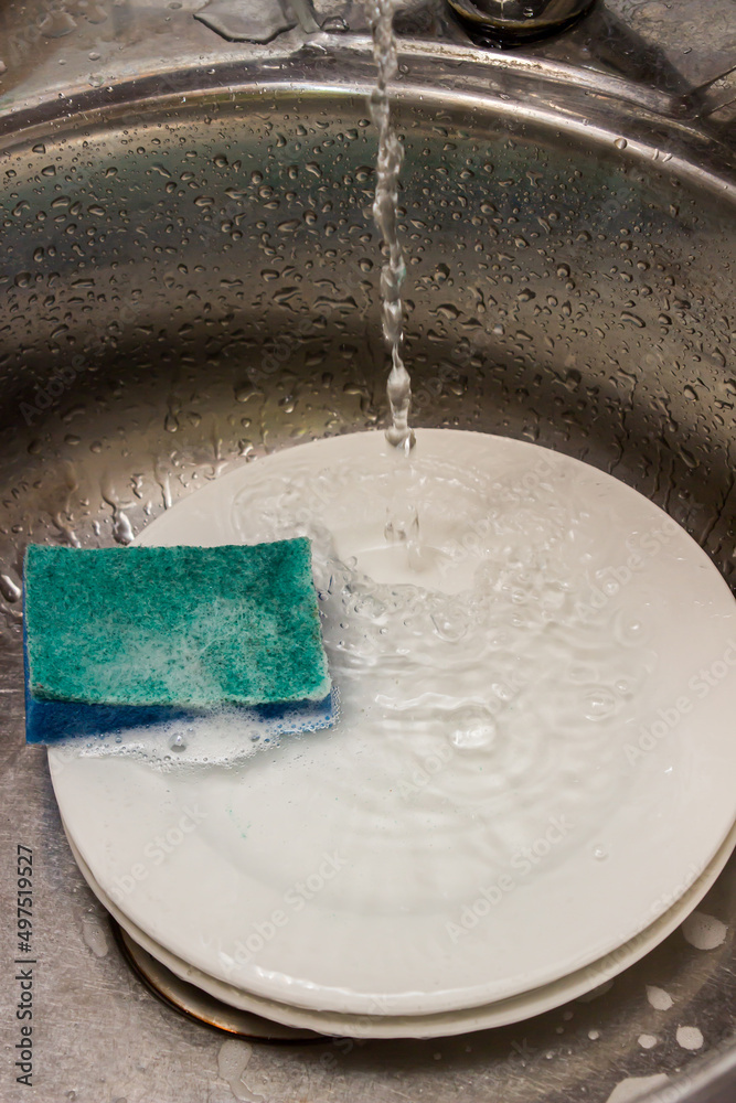 Plates and sponge for washing dishes in the sink. Washing dishes ...