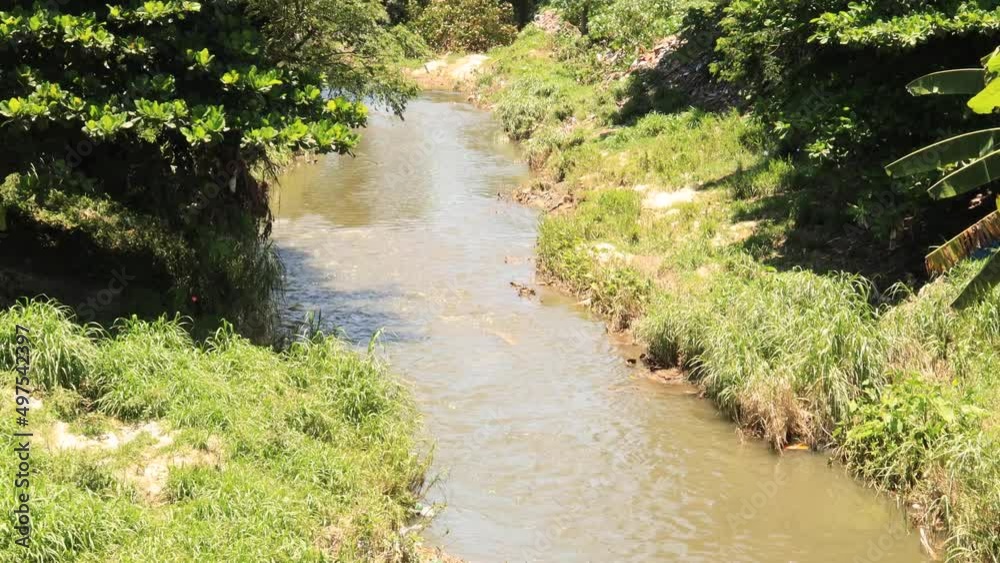 Wild and partly destroyed riverbank with non-biodegradable garbage and ...