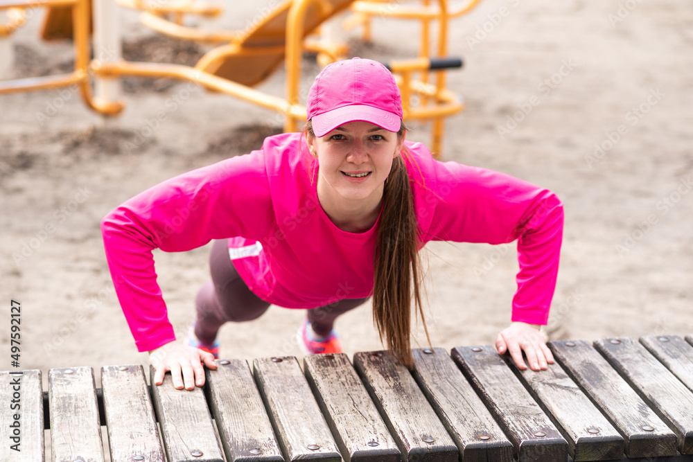Foto de Young happy strong female wearing rose clothes does push-ups ...