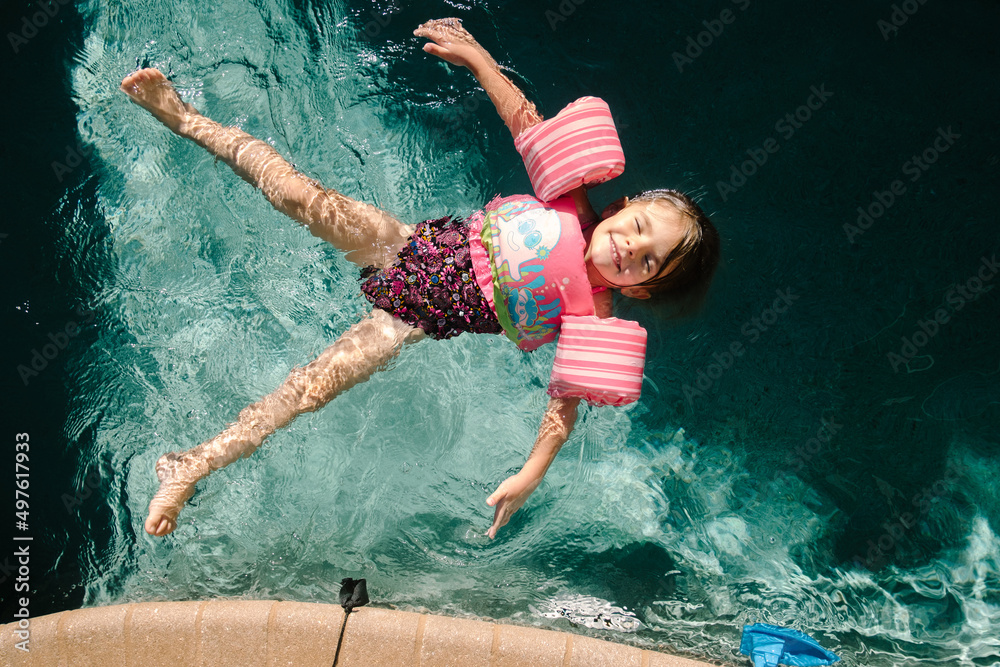 little girl floating on back in swimming pool Stock Photo | Adobe Stock