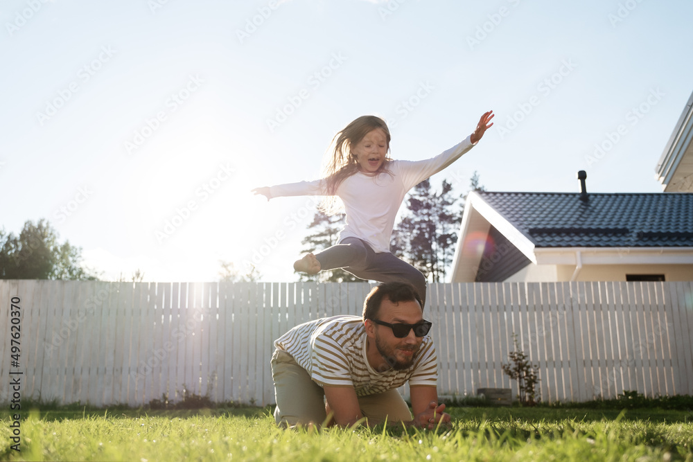 Excited child jumping over dad in backyard Stock Photo | Adobe Stock