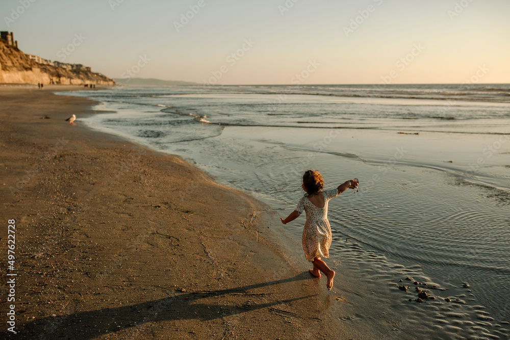 Back view of young girl on beach at sunset Stock Photo | Adobe Stock