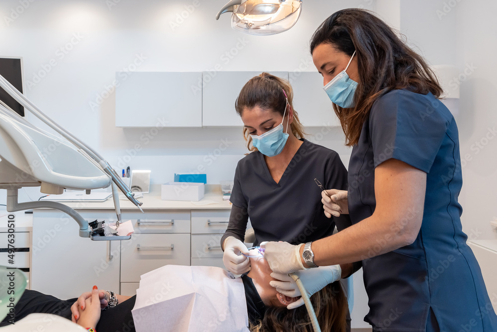 Female dentists treating patient with cheek retractor Stock Photo ...