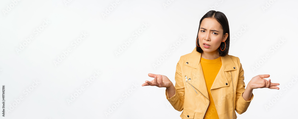Image of confused young asian woman shrugging shoulders, looking ...