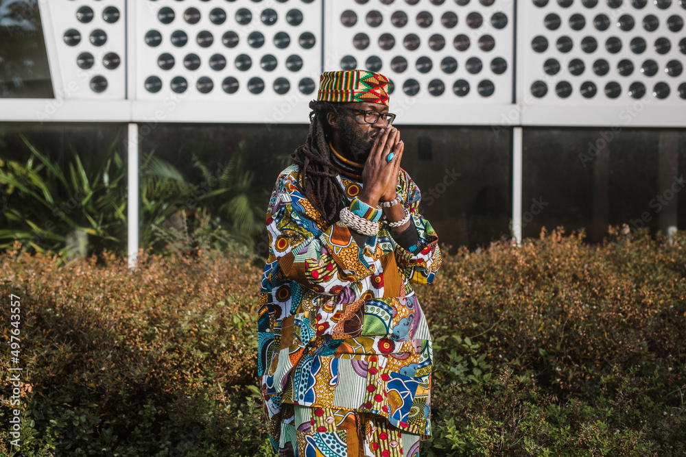 Man in colourful African outfit hands in a prayer Stock Photo | Adobe Stock