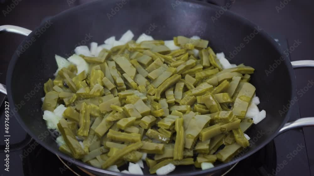 Cactus cacti food being sautéed with chopped onions in frying pan. A ...